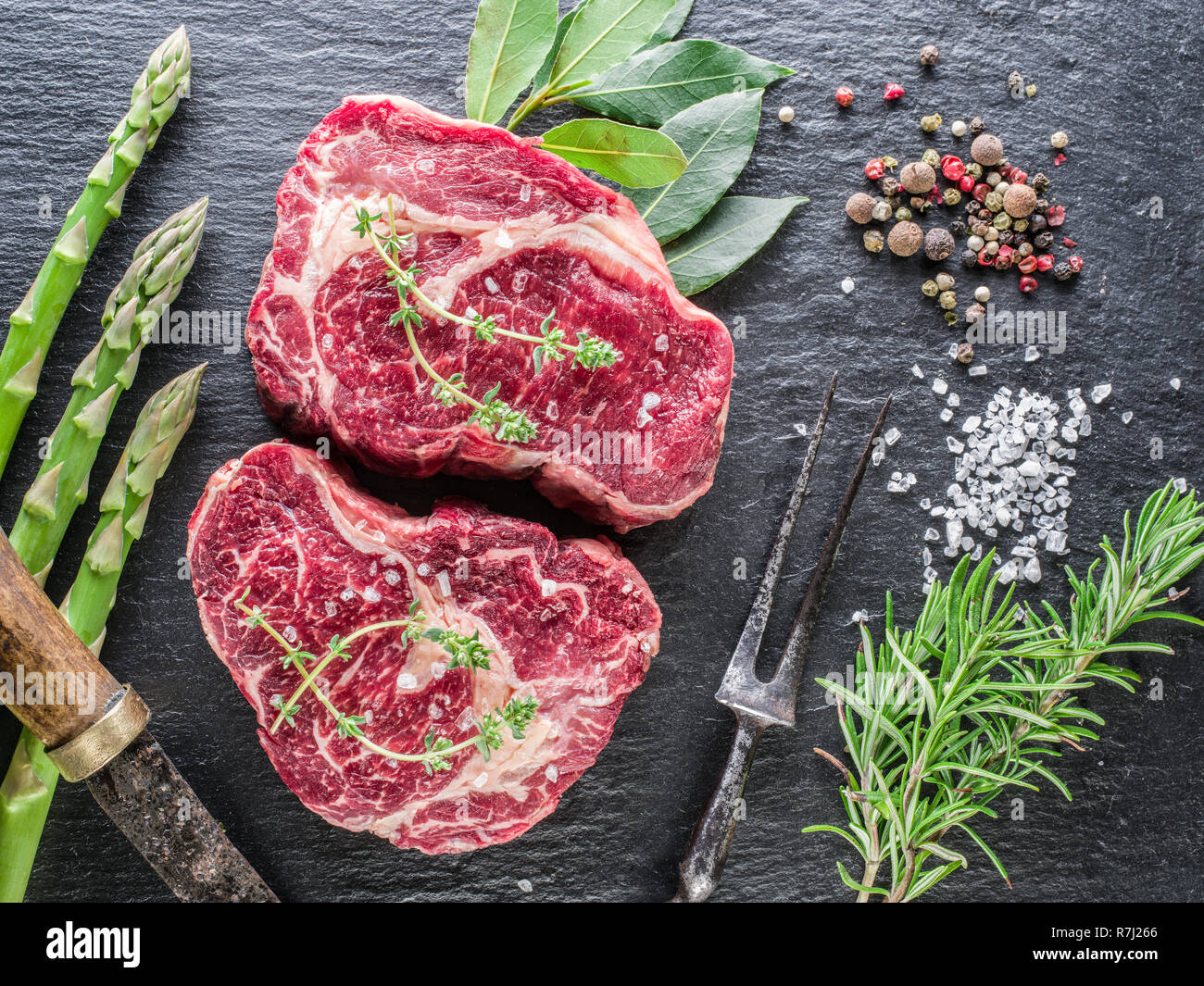 Raw Ribeye steaks or beef steak on graphite tray with herbs. Top view ...