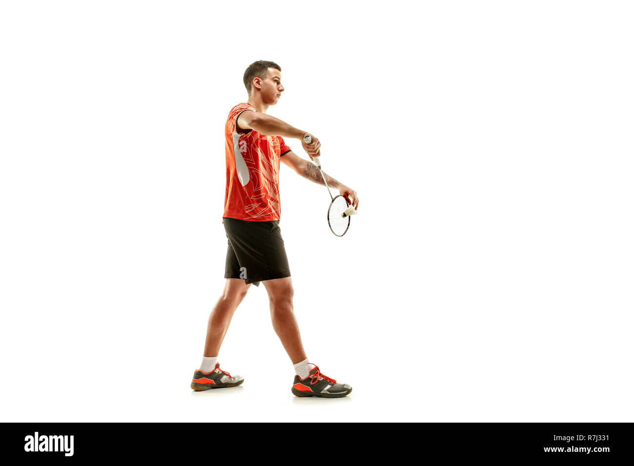 Young man playing badminton over white studio background. Fit male ...