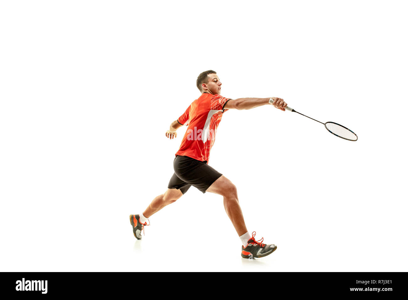 Young man playing badminton over white studio background. Fit male ...