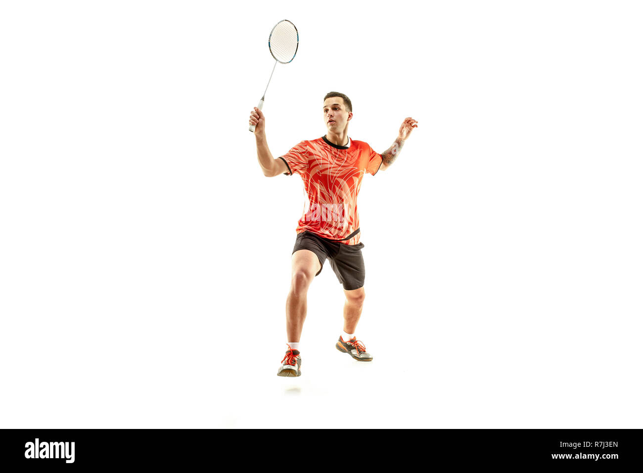 Young man playing badminton over white studio background. Fit male ...
