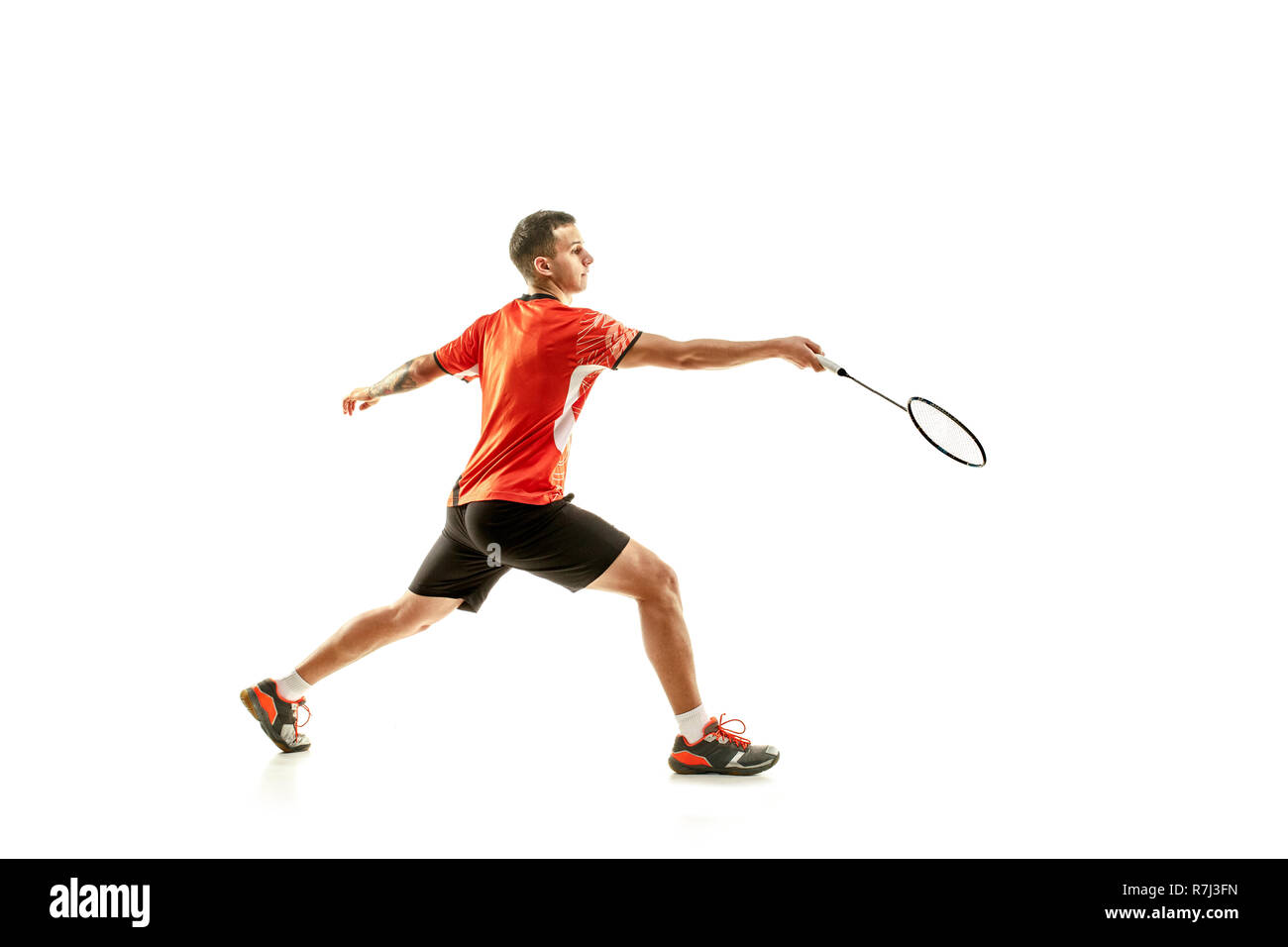 Young man playing badminton over white studio background. Fit male ...