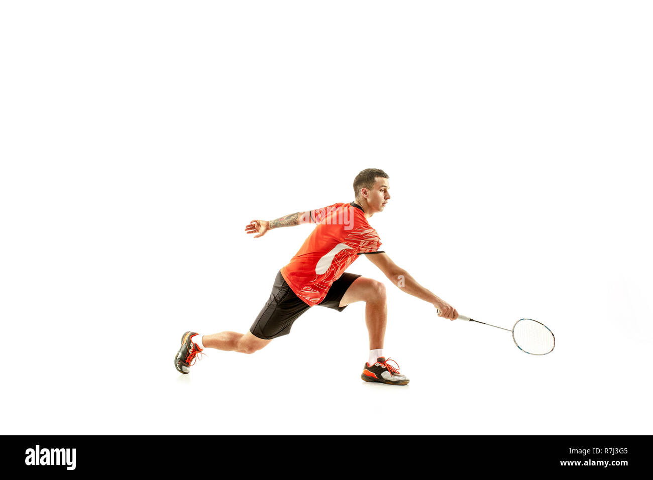 Young man playing badminton over white studio background. Fit male ...