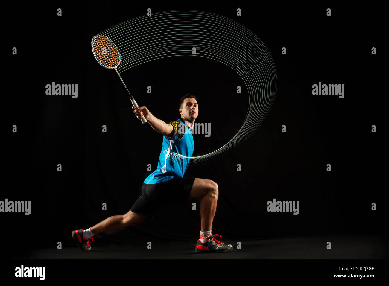 Young man playing badminton over black studio background. Fit male ...