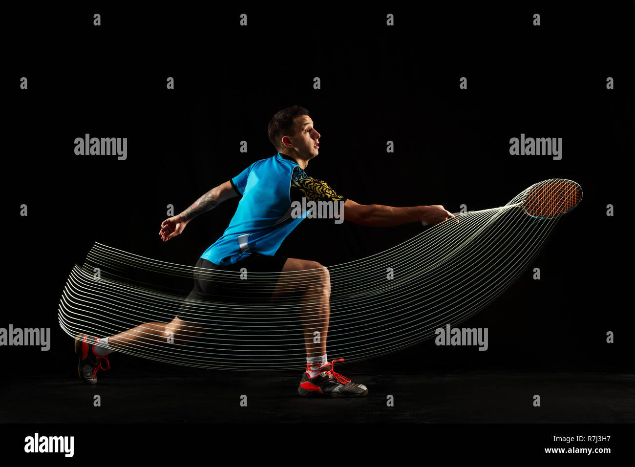 Young man playing badminton over black studio background. Fit male ...