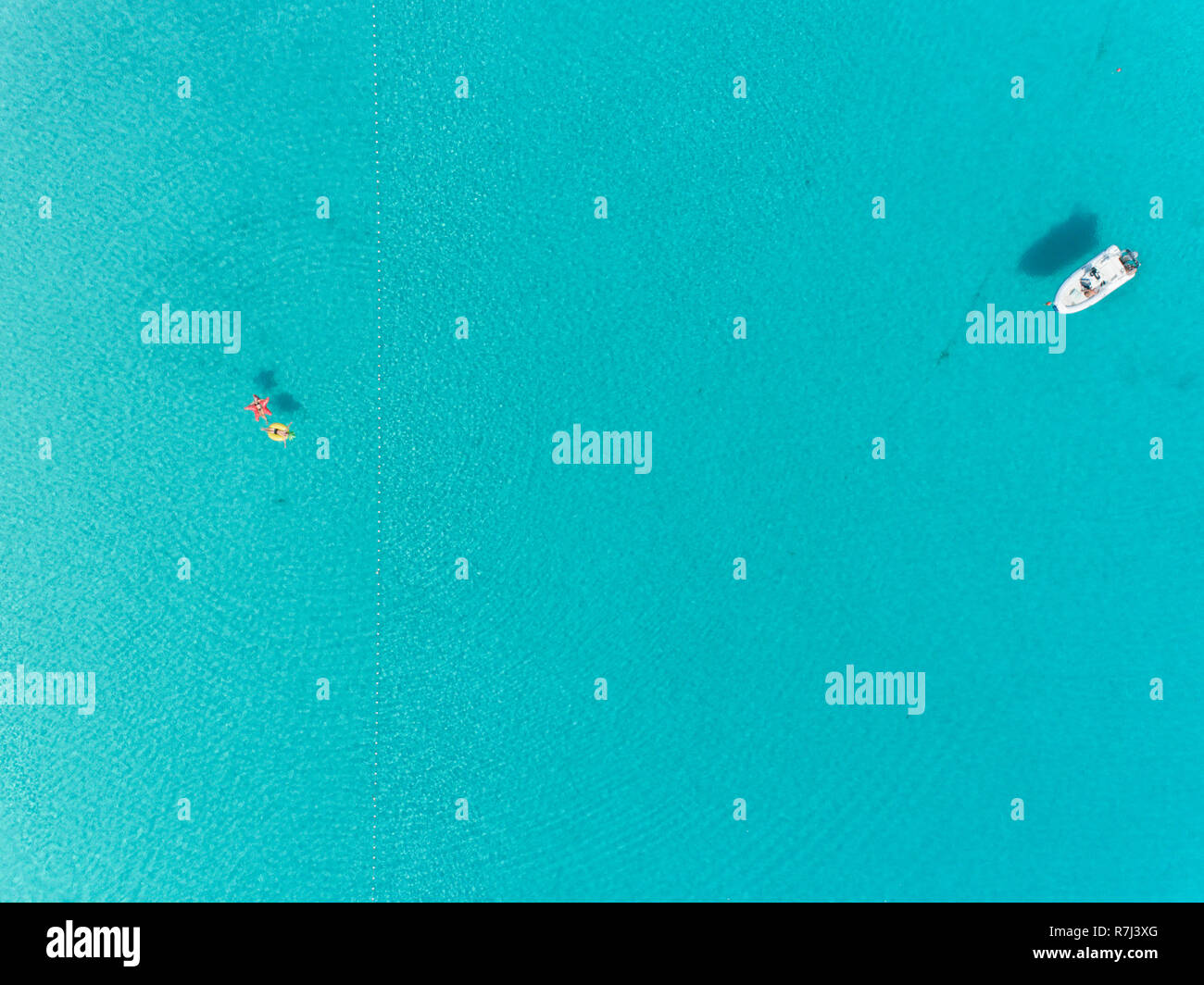 Aerial view of two people floating in open sea on inflatables by white ...