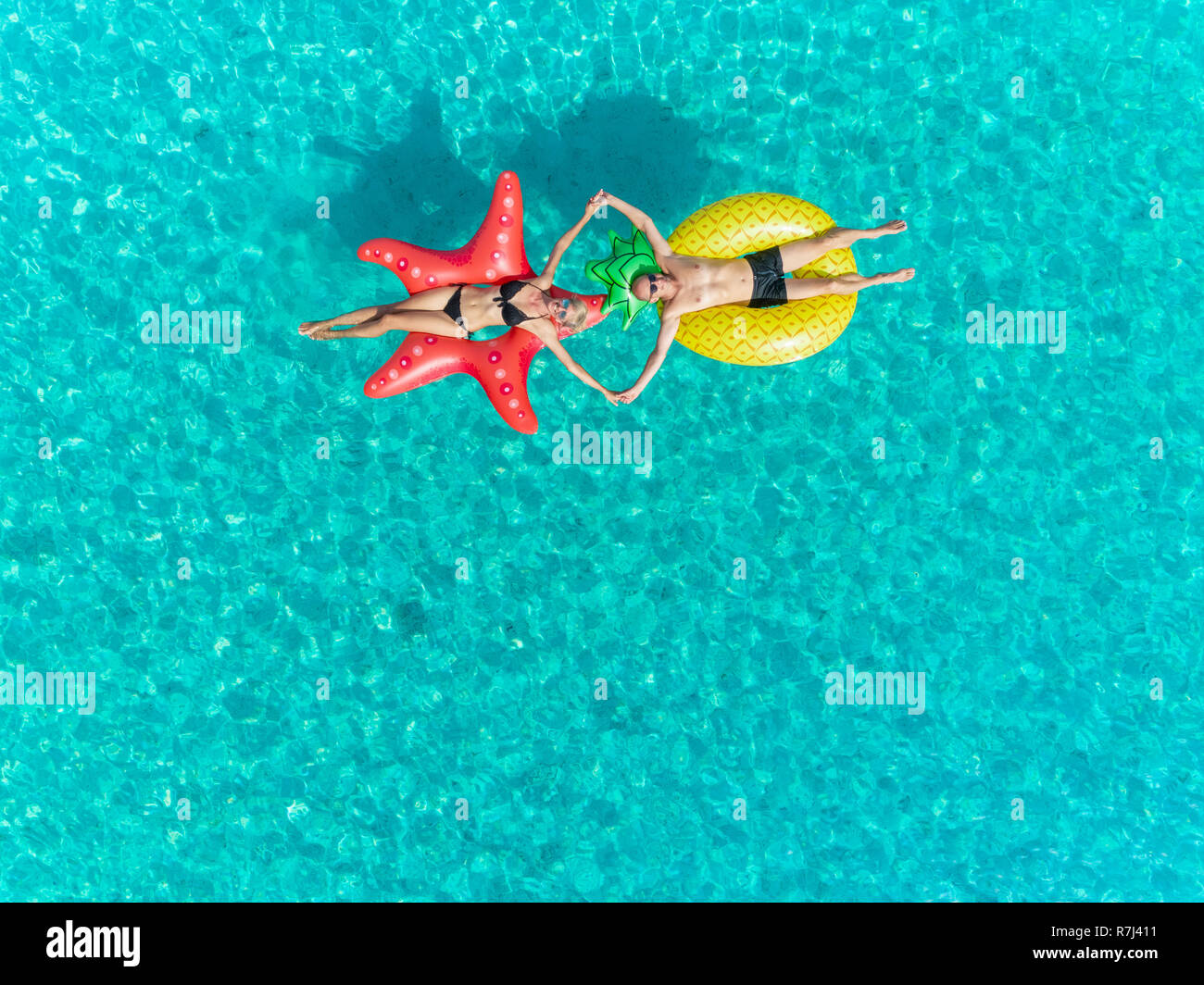 Aerial close up view of man and woman floating on inflatable star and ...