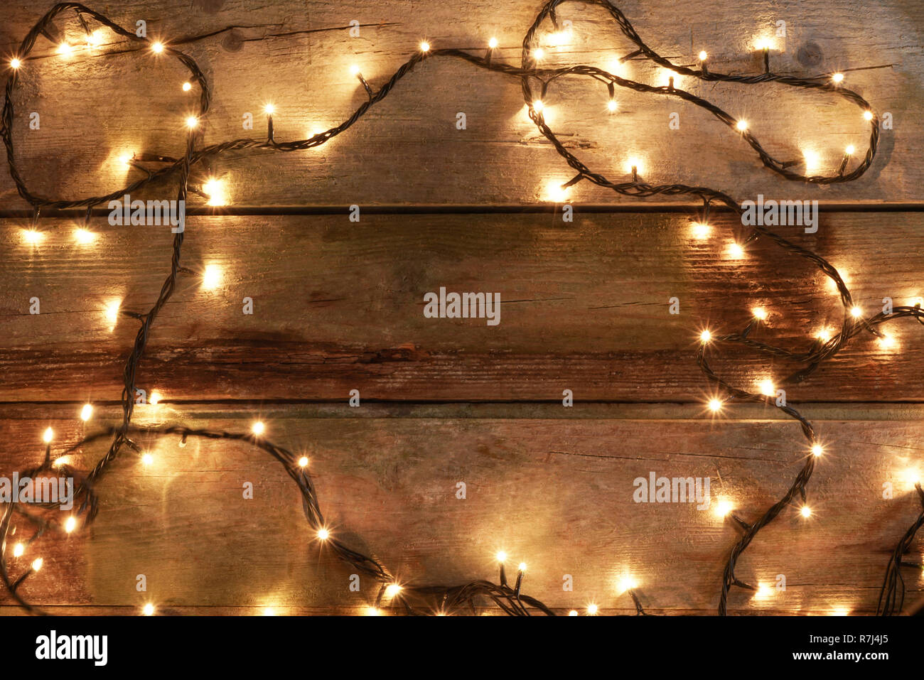 Overhead view of yellow Christmas lights spread over rustic wooden ...