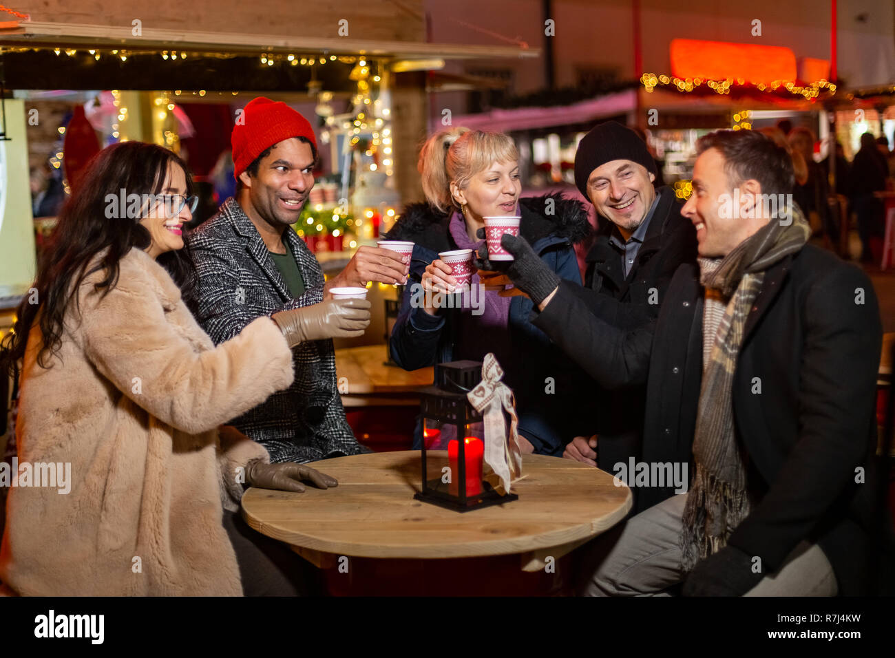 Group of friends laughing and cheering with traditional drink at ...