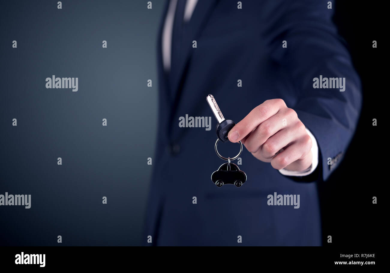 Young businessman hand over keys with empty dark background Stock Photo ...