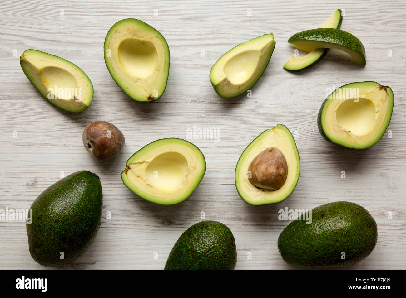 Whole and chopped avocados on white wooden surface, overhead view. Top ...