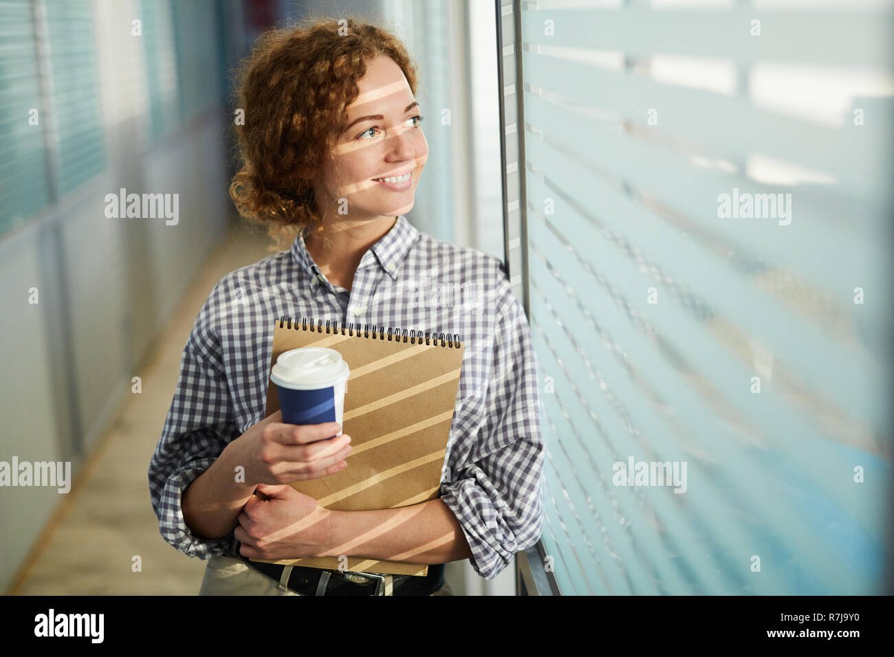 Cheerful attractive lady drinking coffee in corridor Stock Photo - Alamy