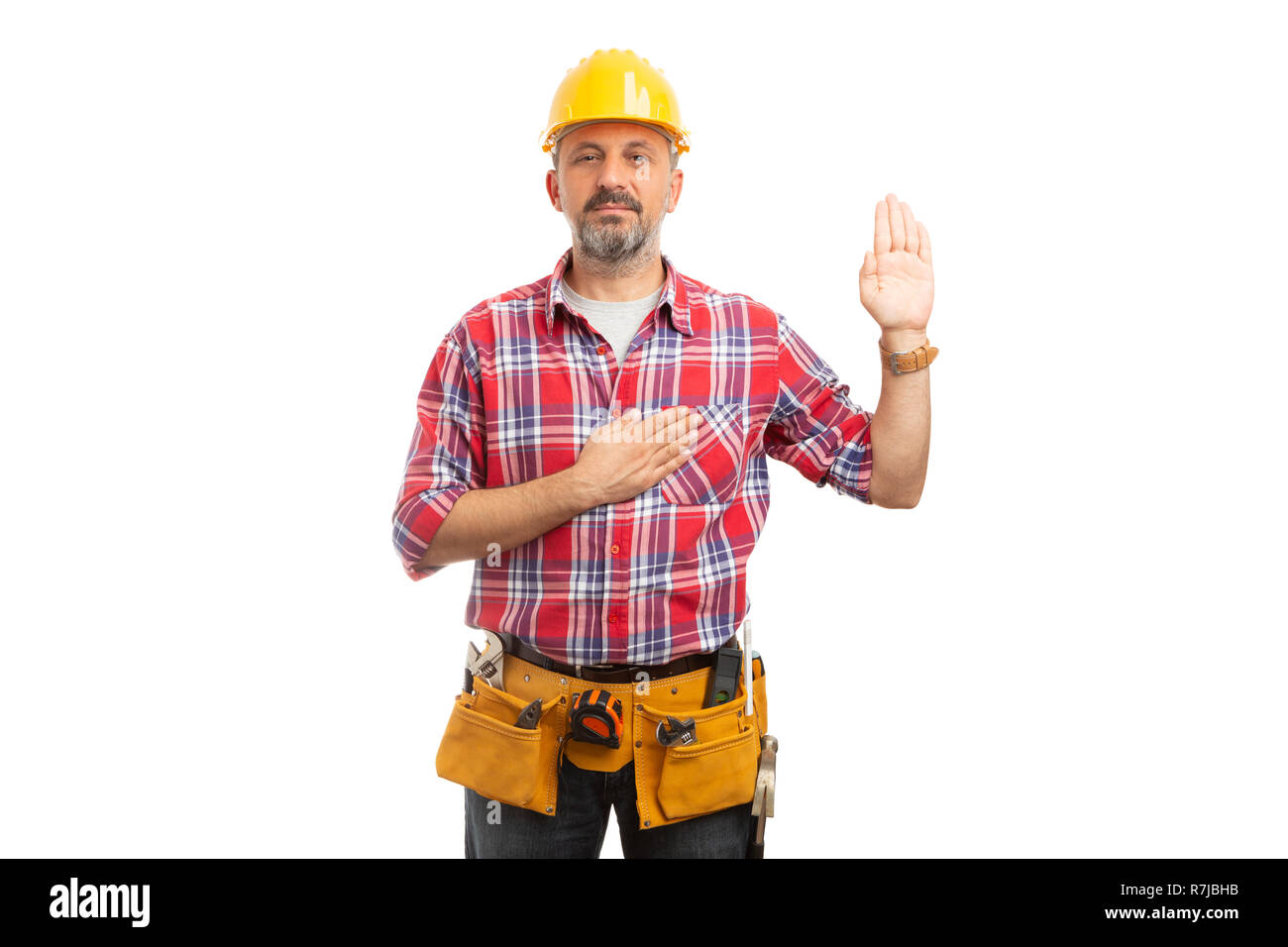 Serious builder swearing with one palm up and other hand on heart ...