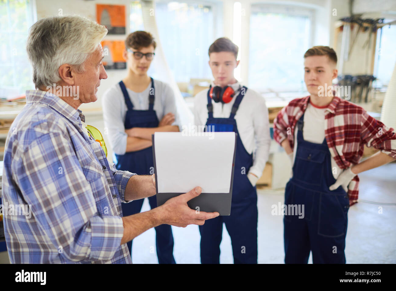 Serious woodworking master explaining project to young students Stock ...