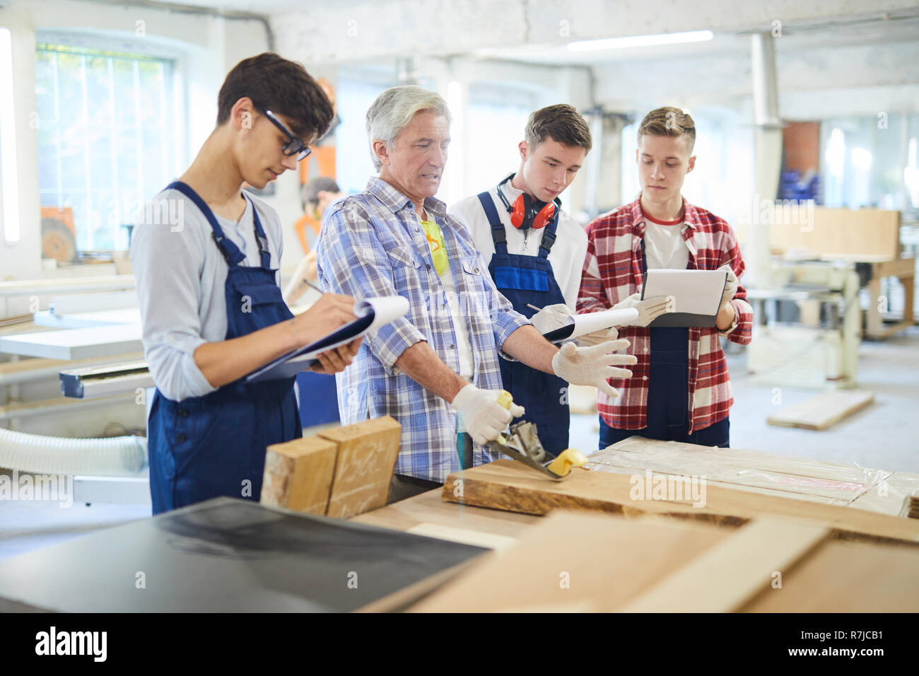 Carpenter teaching students to polish wooden planks Stock Photo - Alamy
