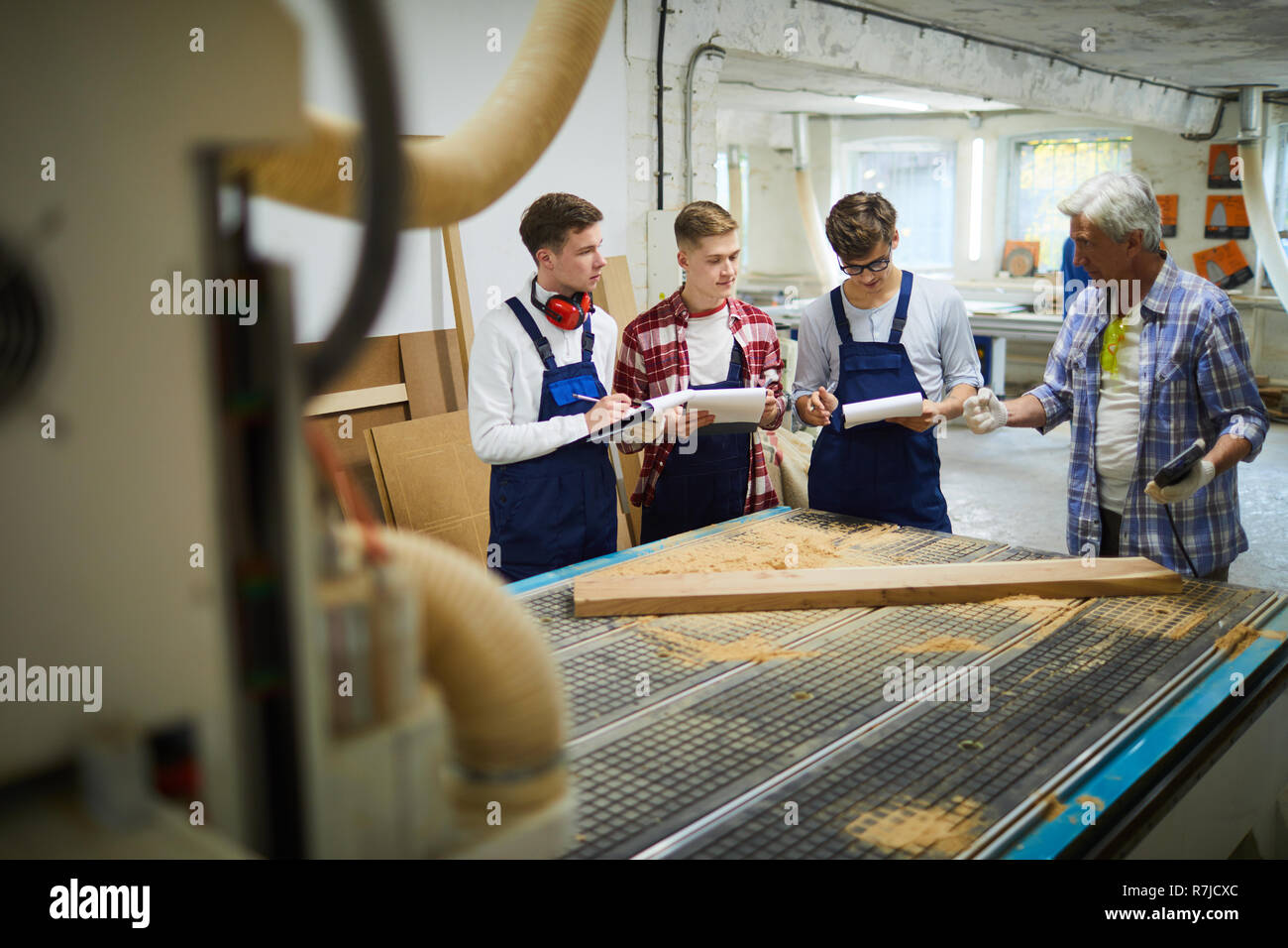 Carpenter demonstrating woodworking process to young students Stock ...