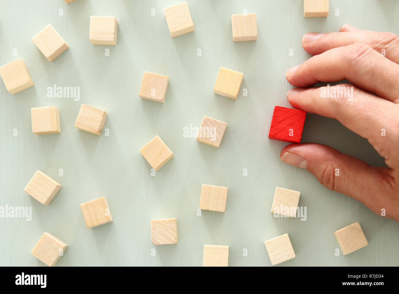 One different red cube block among wooden blocks. Individuality ...