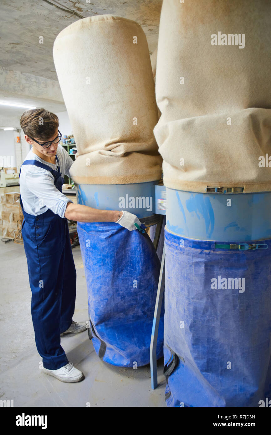 Young industrial worker fixing rubbish sack to tube Stock Photo - Alamy
