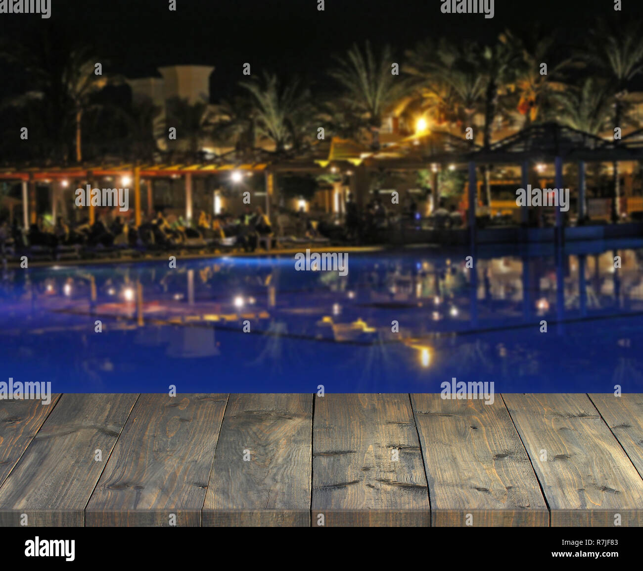 Empty wooden plank with view to evening tropic party. Table top with at ...