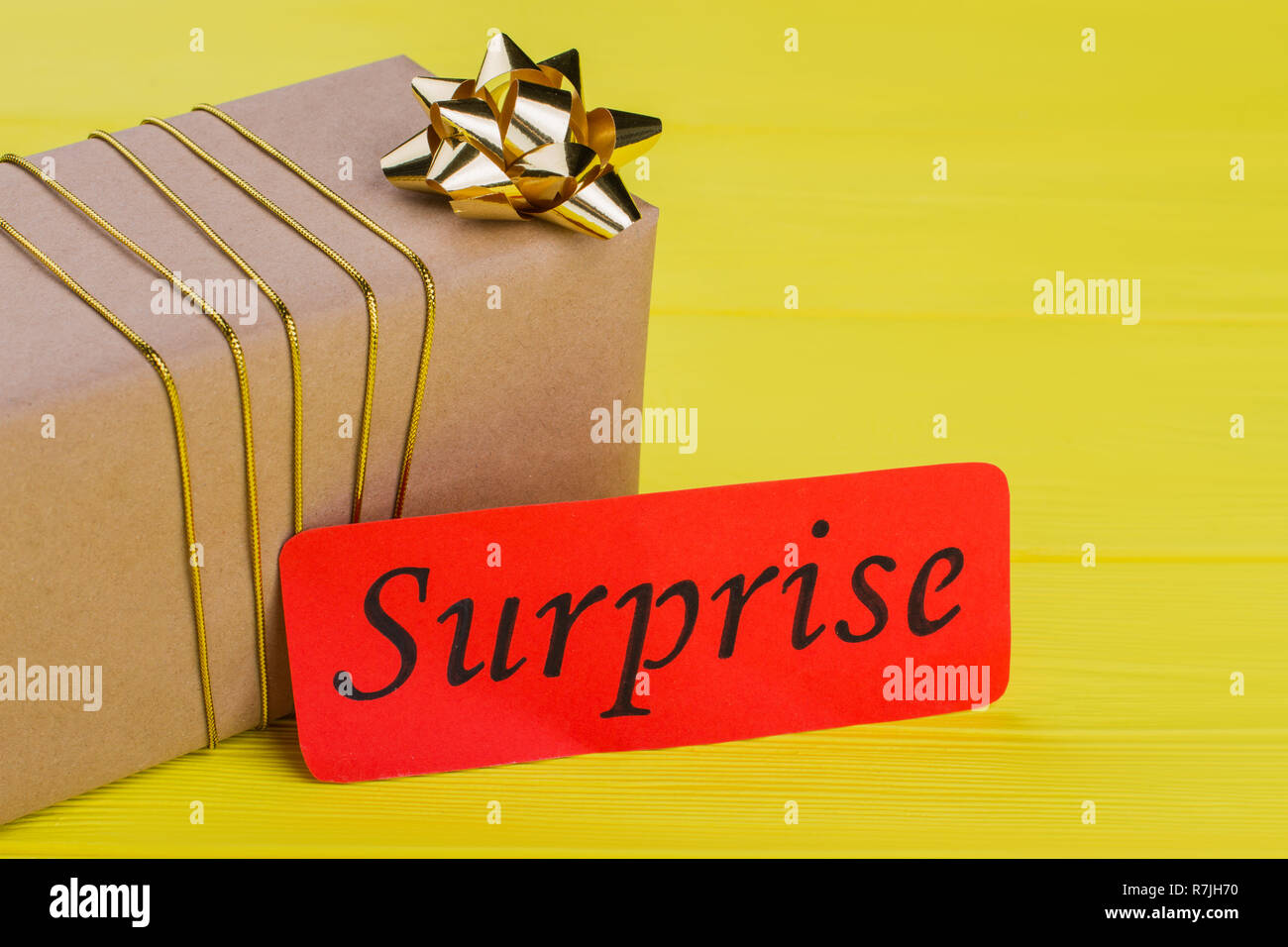 Kraft gift box and surprise note. Close up. Yellow wood background ...