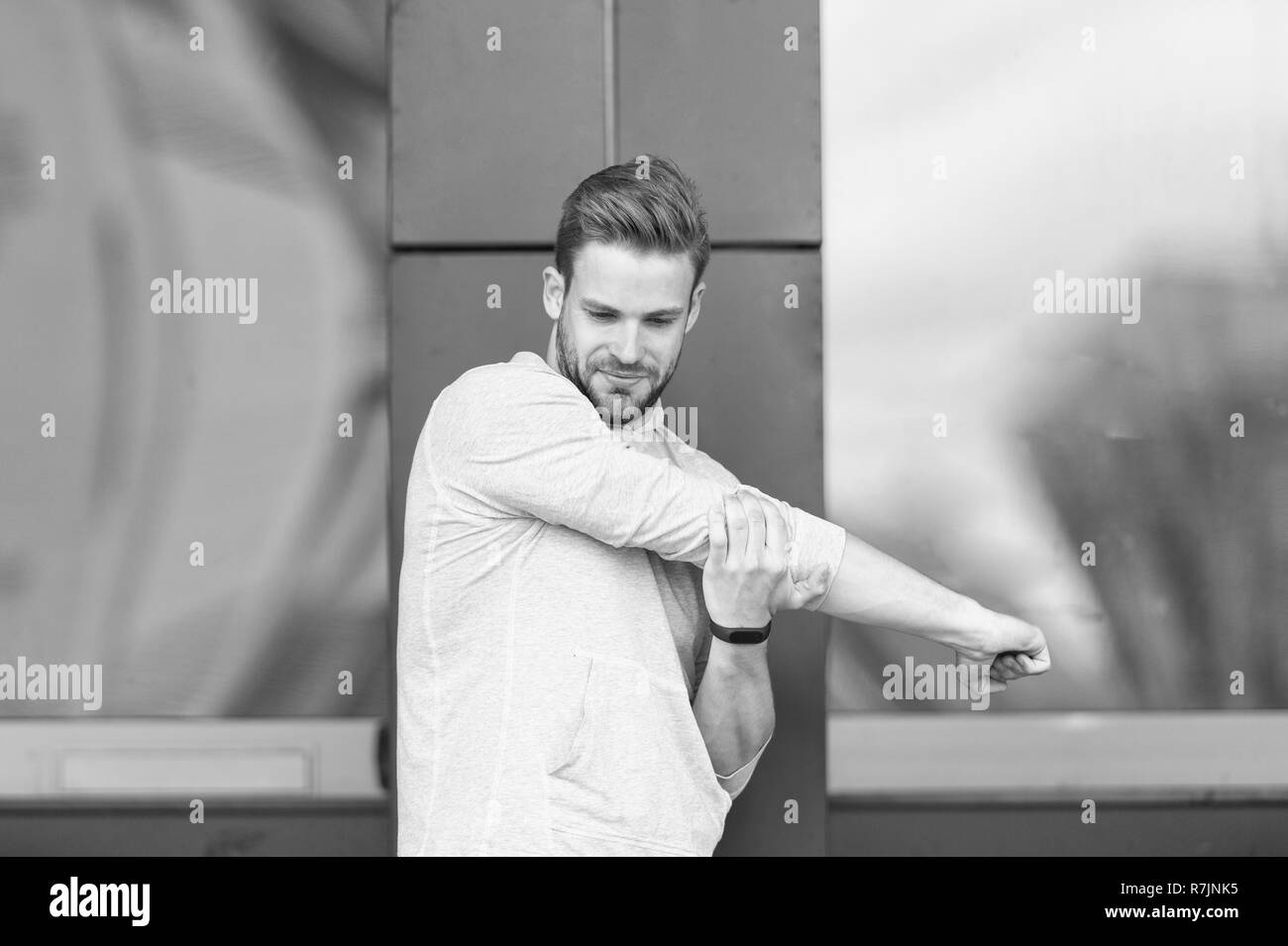 Man athlete concentrated face stretching arms before workout, urban ...
