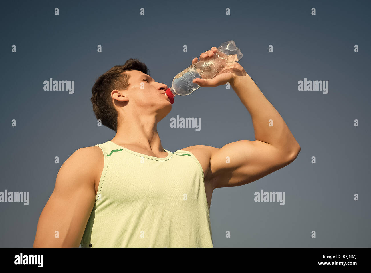 Man drinking water from bottle on sunny day. Bodybuilder with muscular ...
