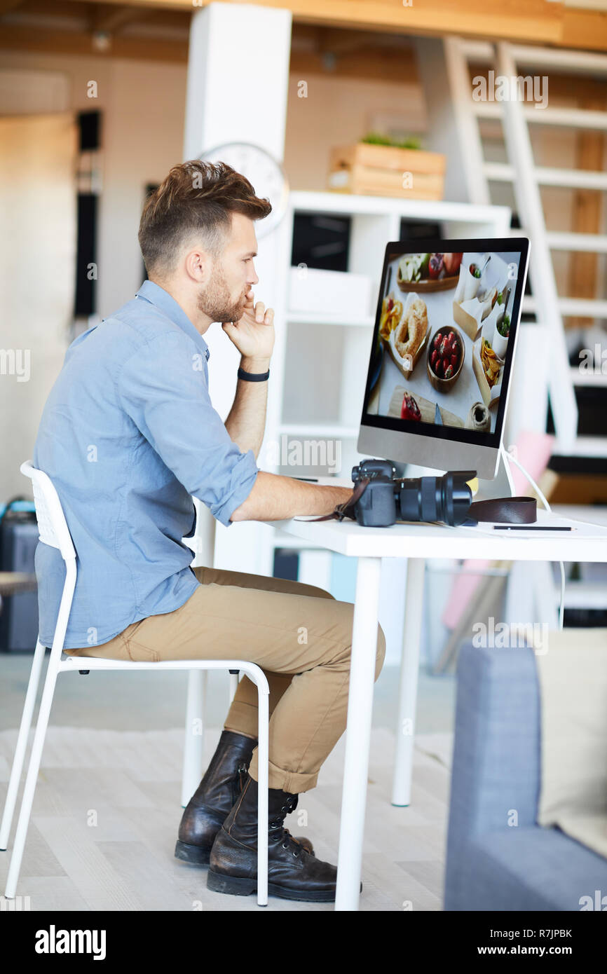 Full length side view portrait of male photographer editing photos ...