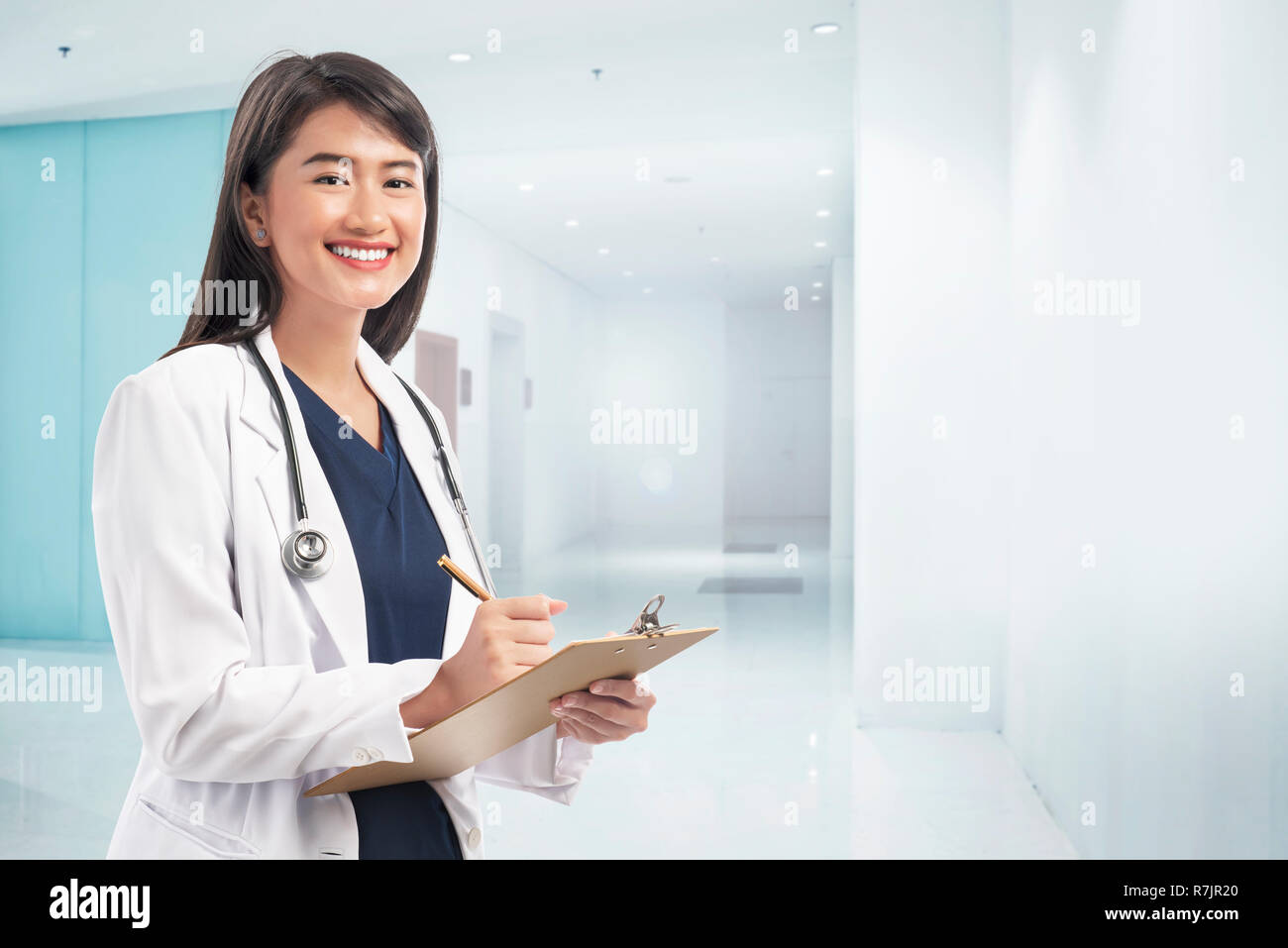 Smiling asian doctor woman wearing lab coat writing notes on the ...