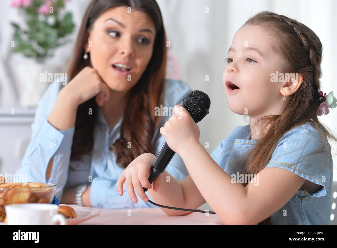 Portrait of little girl with mother singing karaoke Stock Photo - Alamy