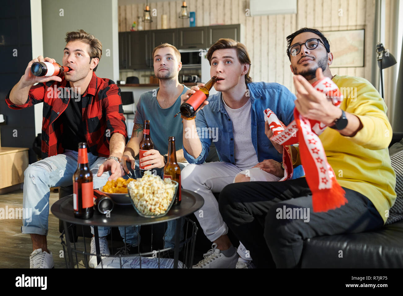 Concentrated football fans sitting with drinks and waiting for the goal ...