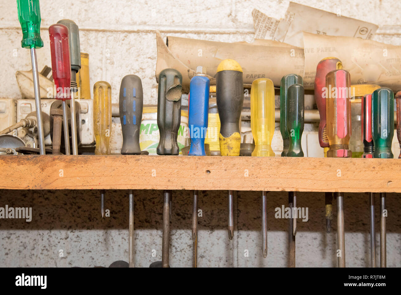 Old sandpaper and screwdrivers stored upright in holes drilled into a ...