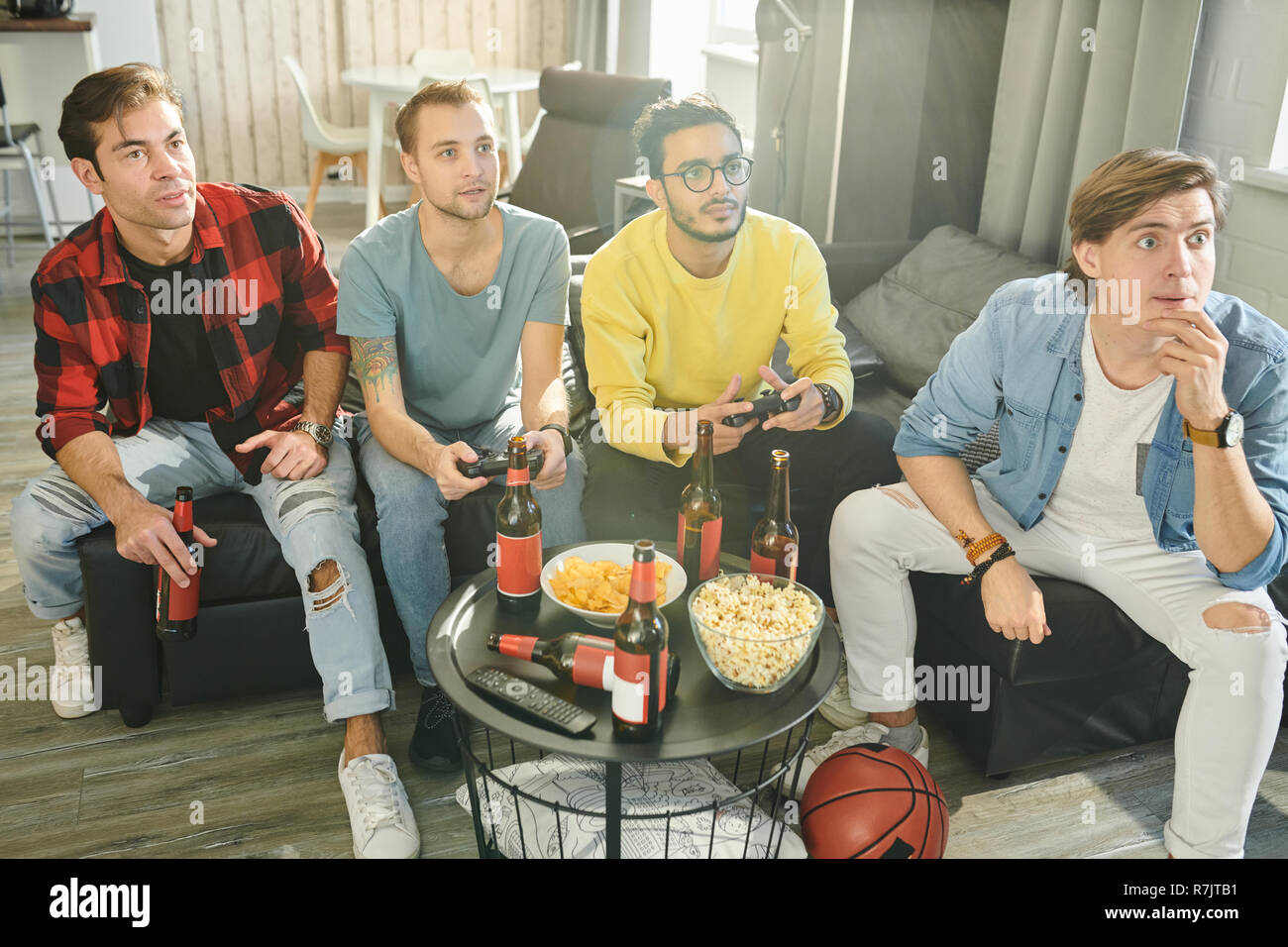 Group of friends playing video games on sofa, they divided into two ...