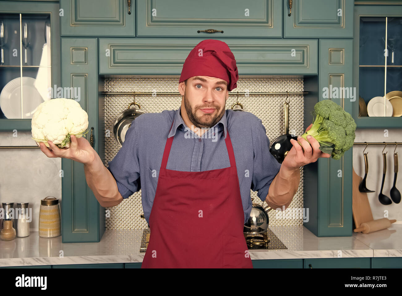 Guy chef with surprised face hold cauliflower and broccoli vegetable in ...