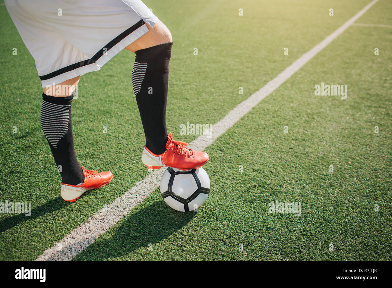 Picture of lower part of body football player. He stand on green field ...
