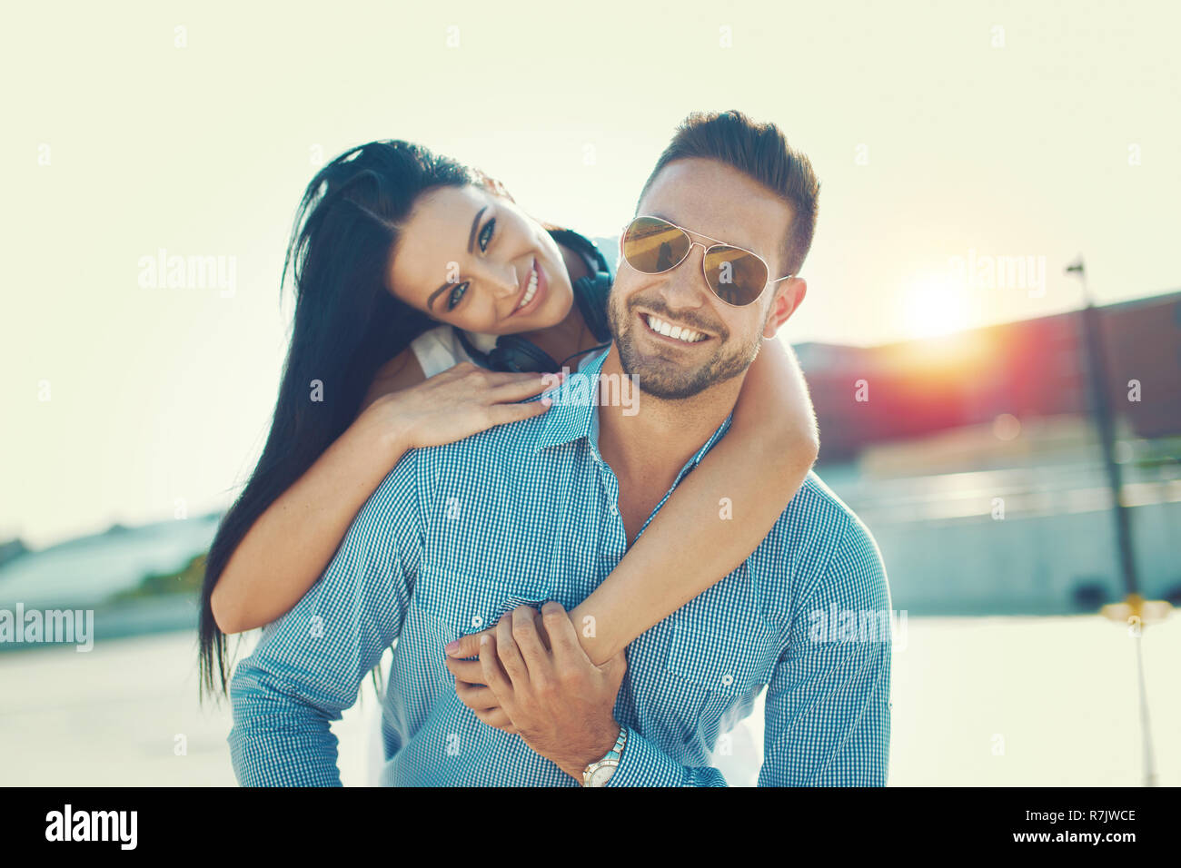 Happy young trendy couple smiling piggyback pose at oudoors Stock Photo ...