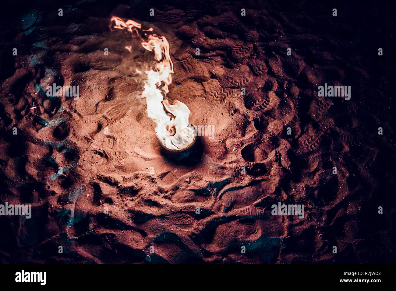 Fire in the top of a sand pyramid on the beach with incoming tide ...