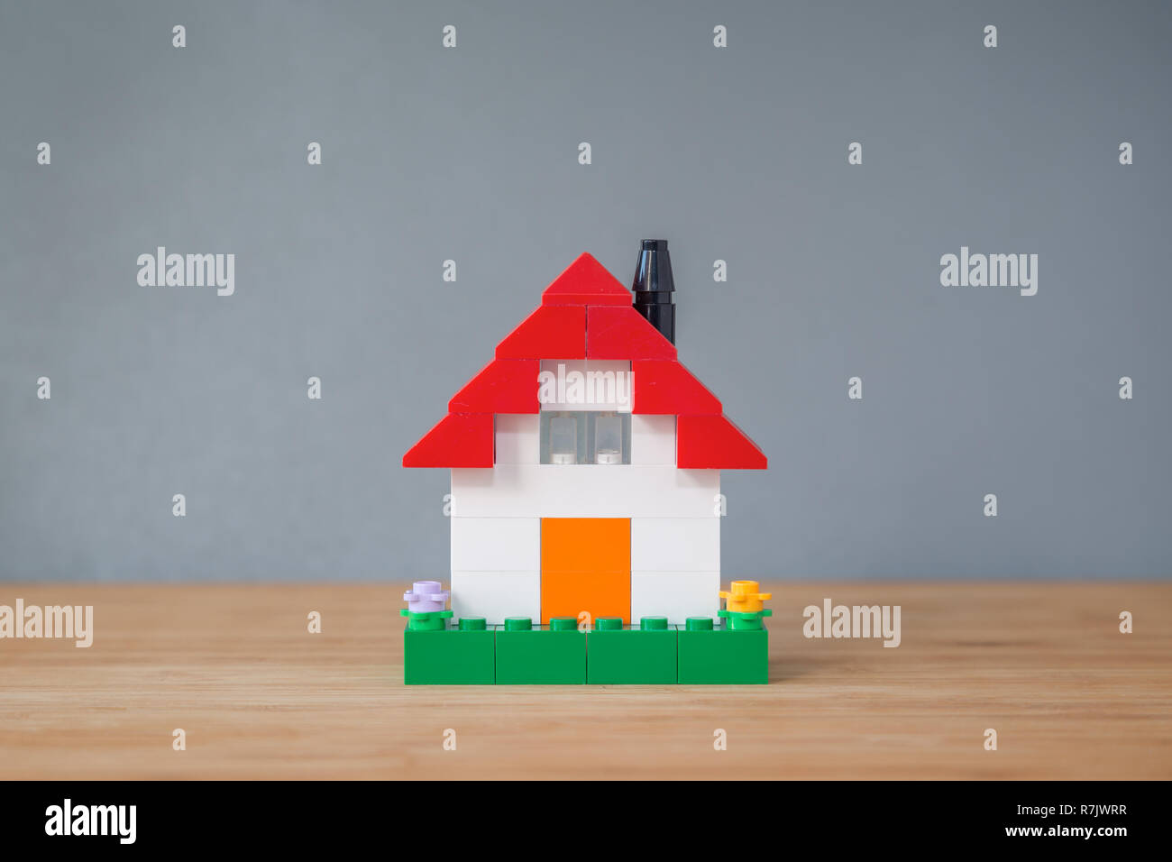 Small and simple house made of toy building bricks, on a wooden surface ...