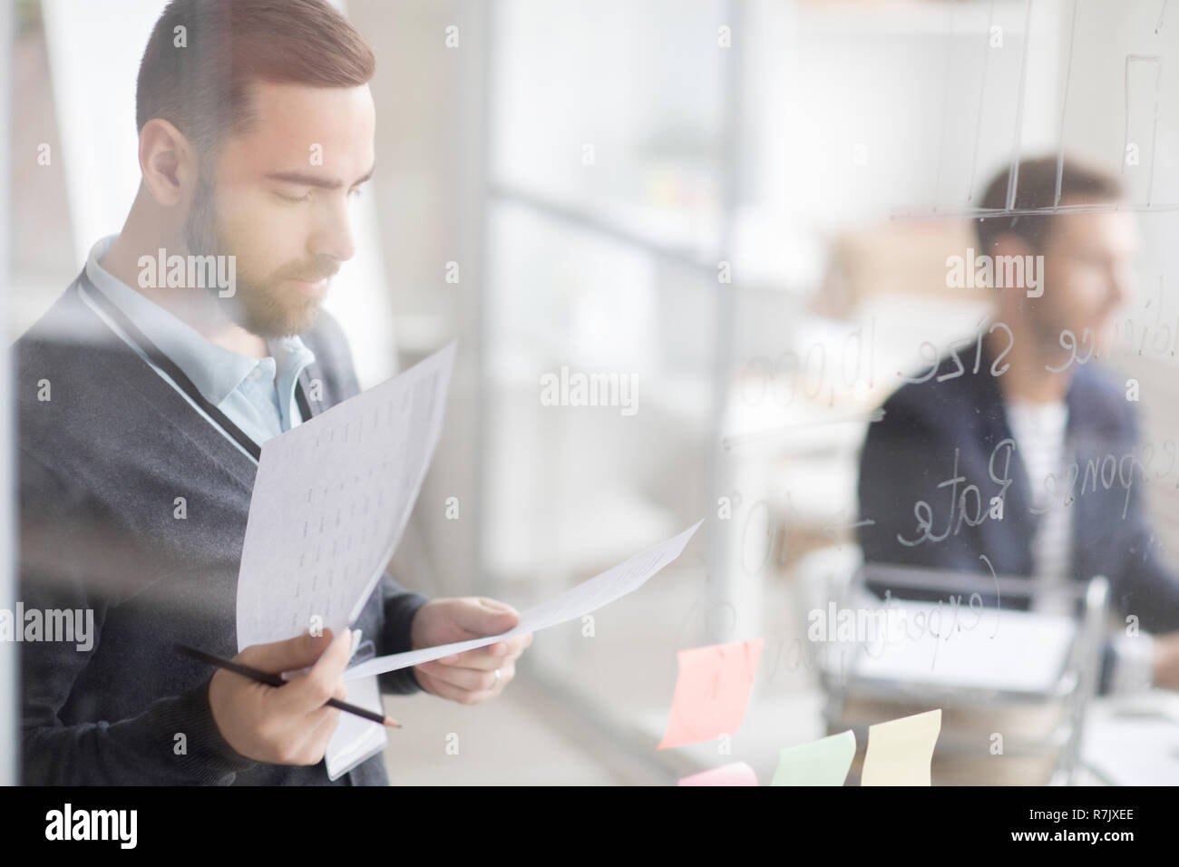 Side view portrait of handsome bearded man reading documents standing ...