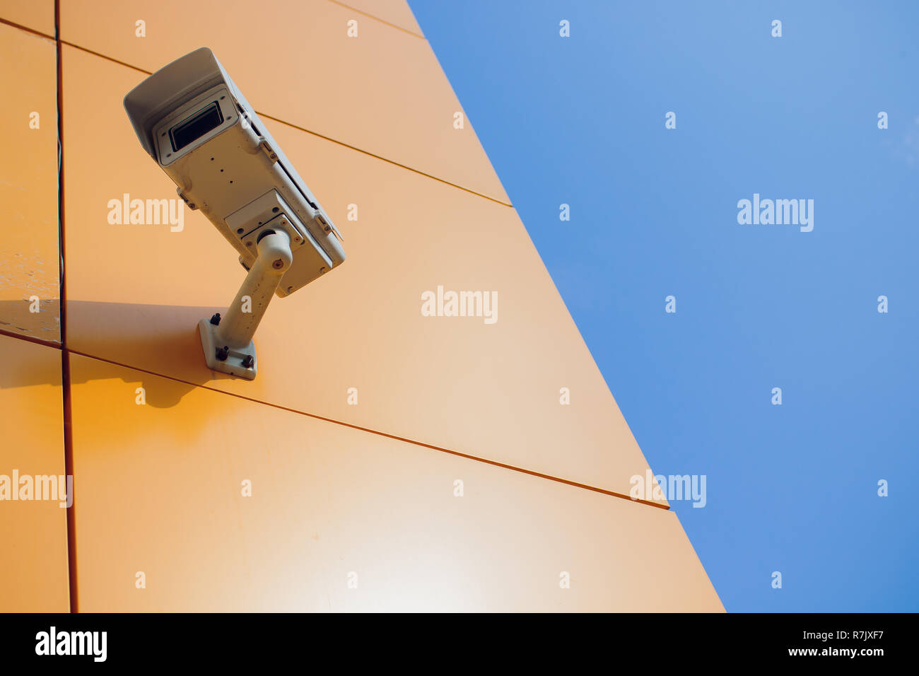 Modern CCTV camera on wall. A blurred night cityscape background ...