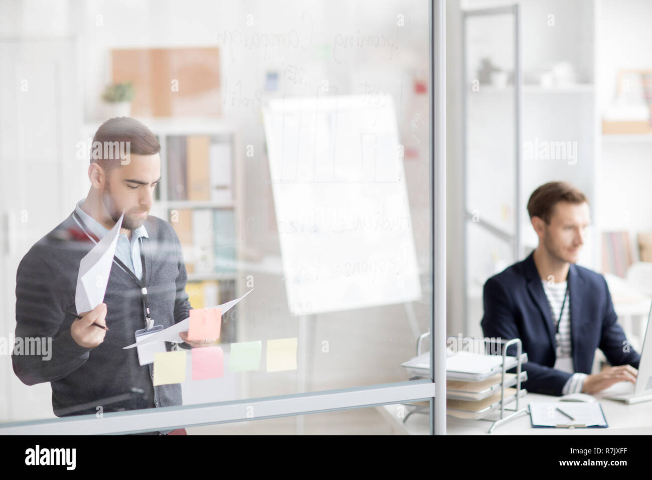 Portrait of modern bearded man reading documents while planning work ...