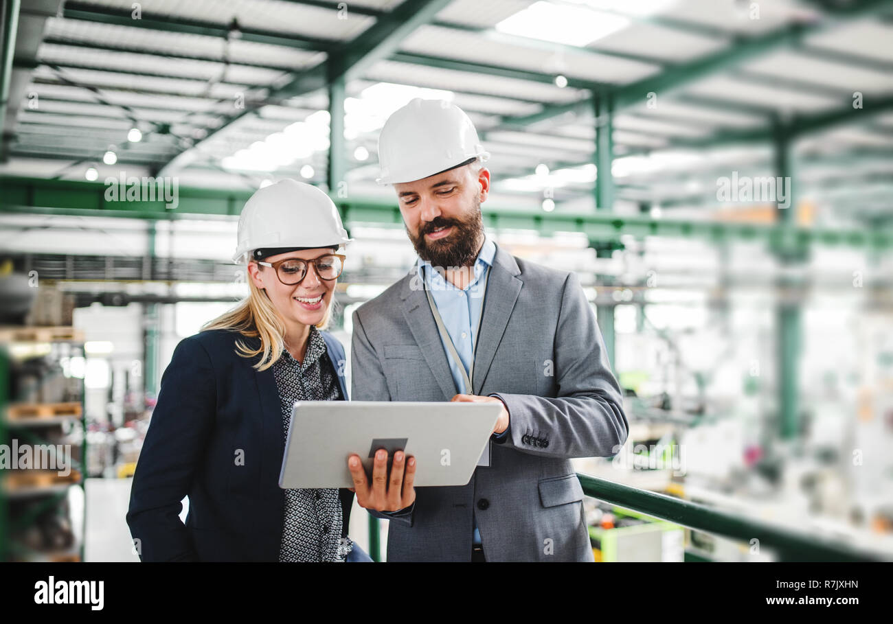 A portrait of an industrial man and woman engineer with tablet in a ...