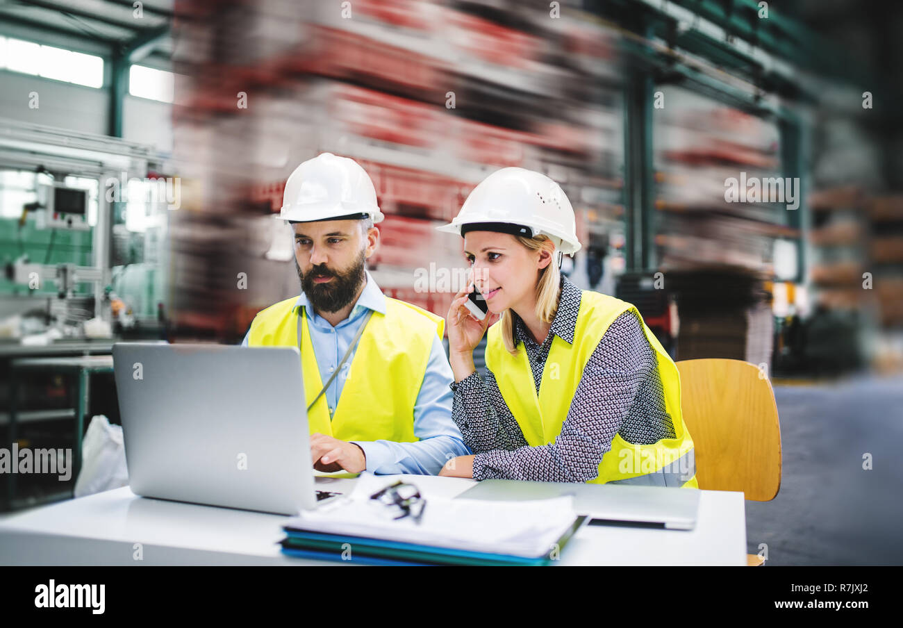 A portrait of an industrial man and woman engineer with laptop in a ...