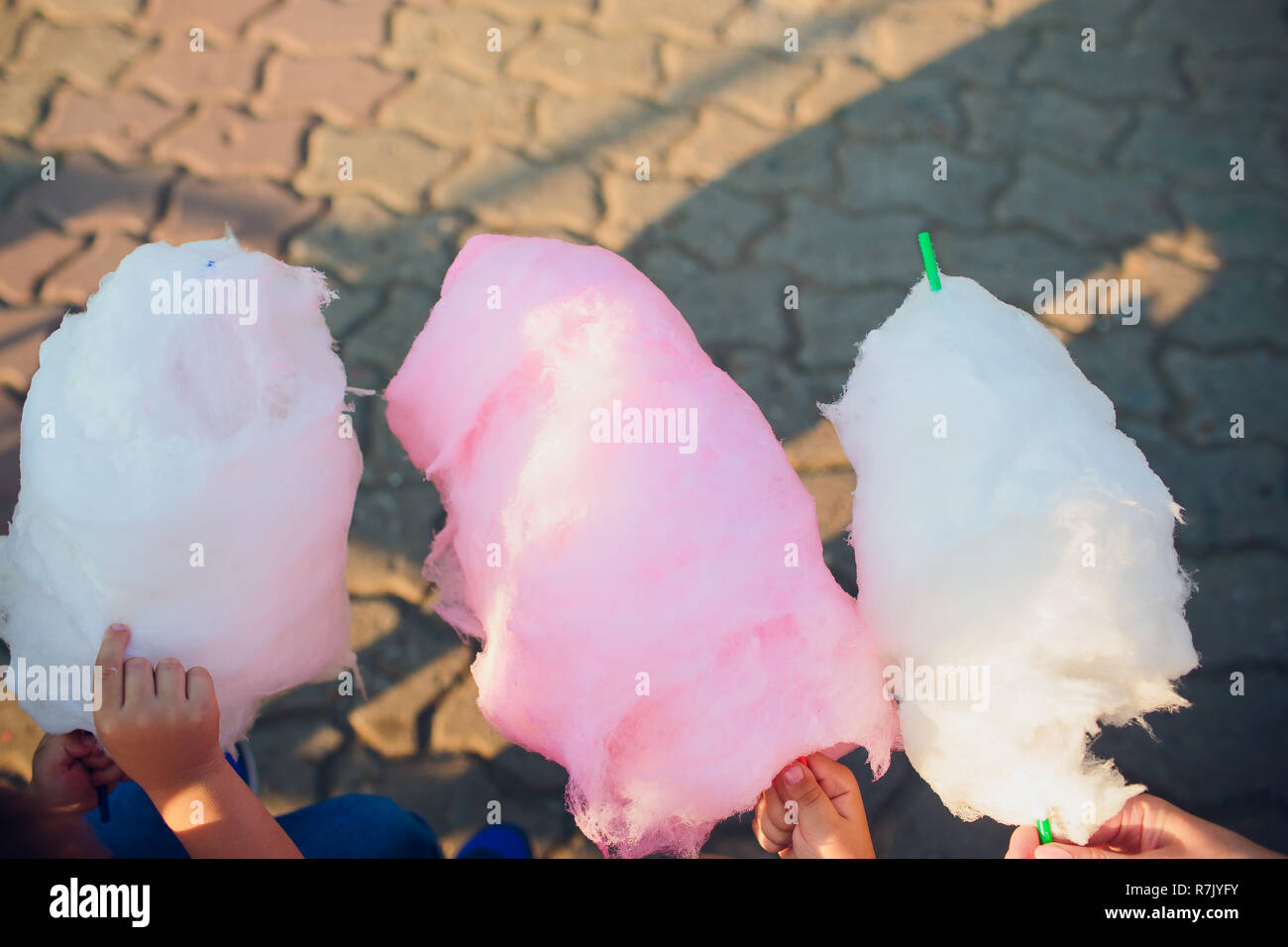 The hands of girl holding pink cotton candy in the background of blue ...