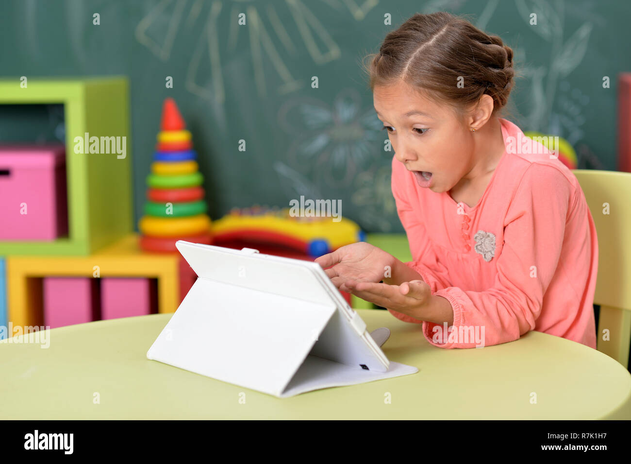 Portrait of cute little girl using tablet Stock Photo - Alamy