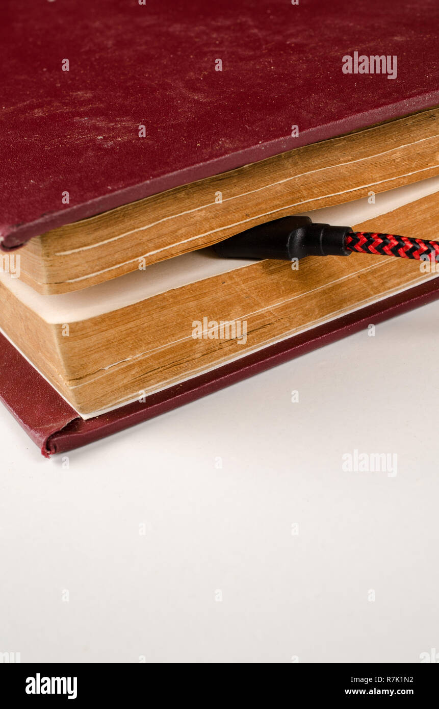 Old book with a battery charging cable, a concept of analog versus ...