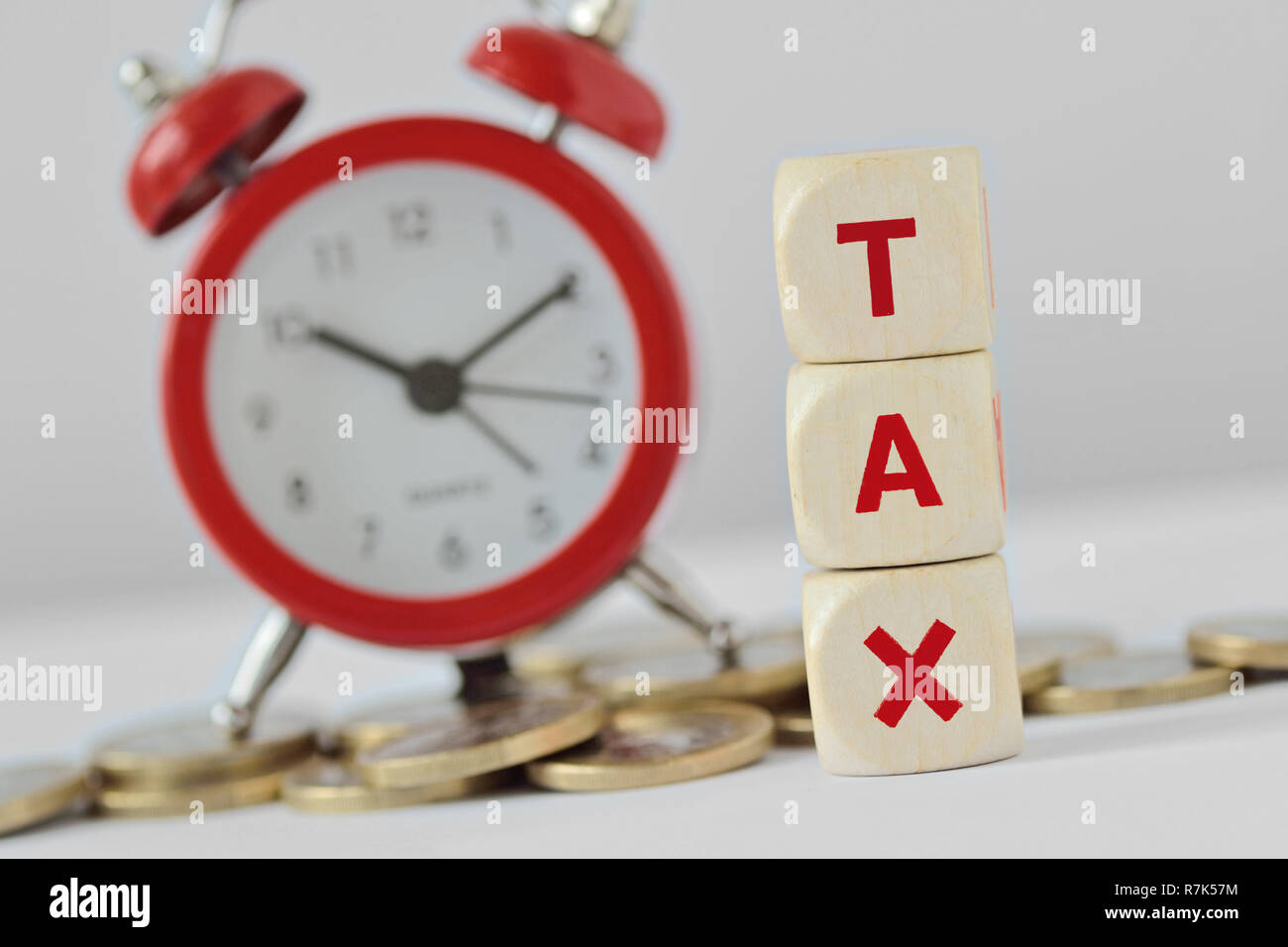 The word Tax written with wooden blocks and alarm clock on coins in the ...