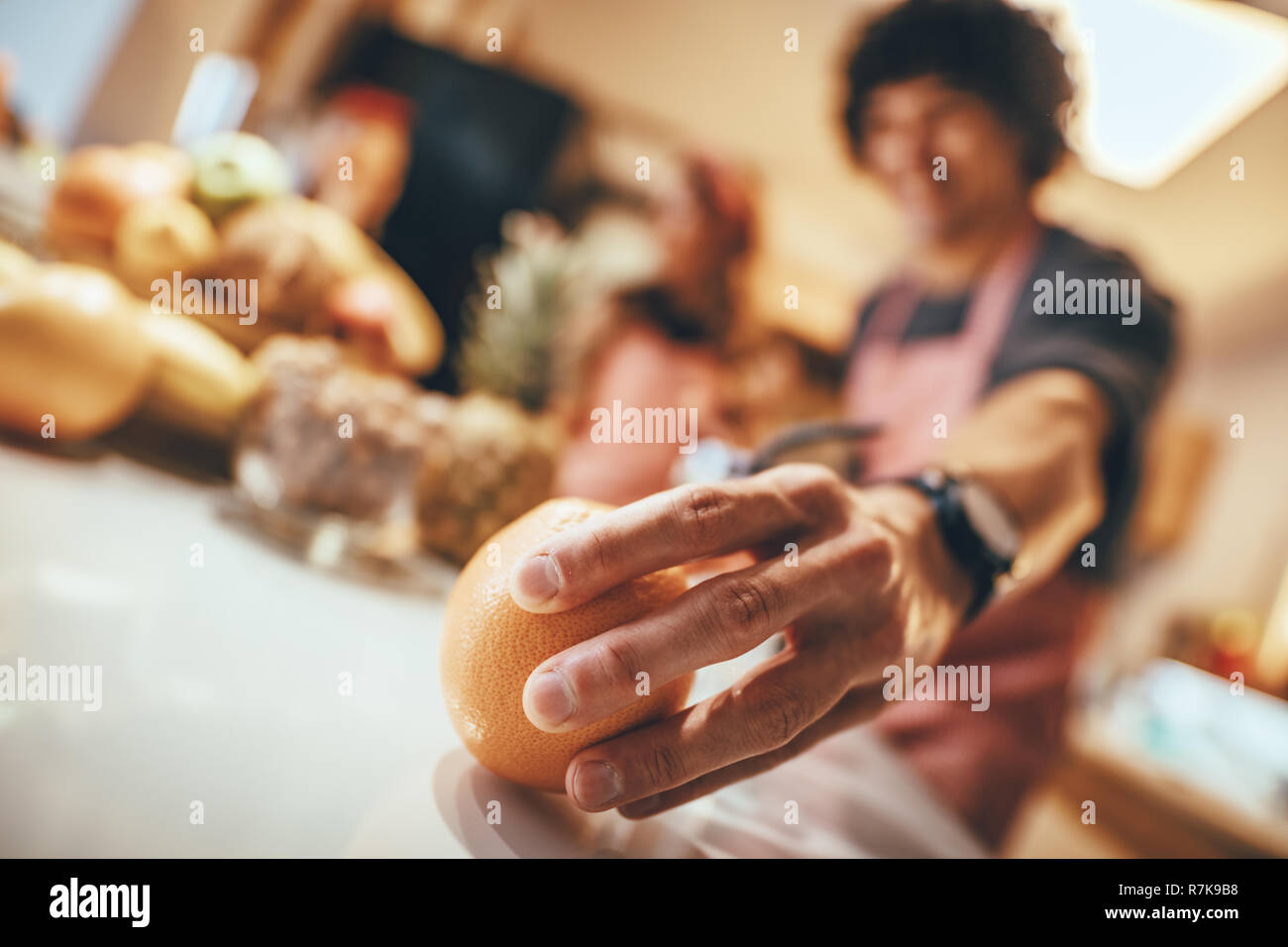 Close up on young man's hand holding mandarin in domestic kitchen Stock ...