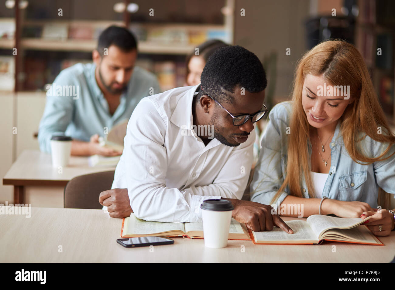 group of happy students reading books and preparing to exam in library ...