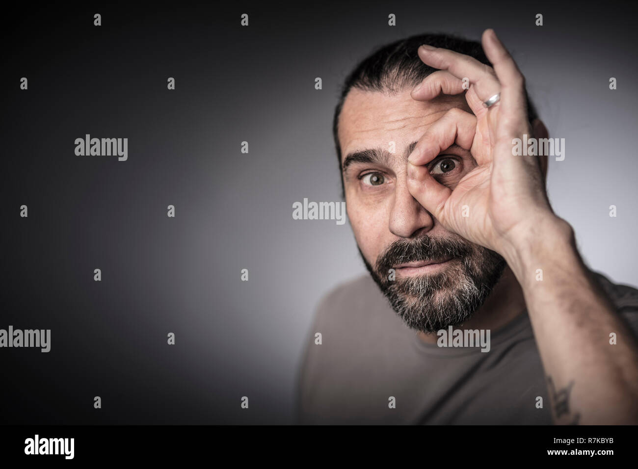 studio portrait of man looking through his closed hand Stock Photo - Alamy