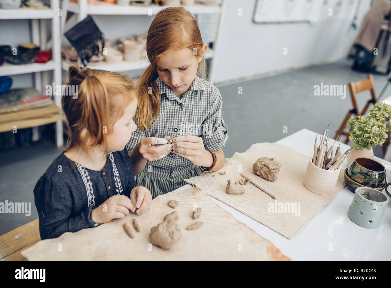 ginger sisters making objects from clay Stock Photo - Alamy