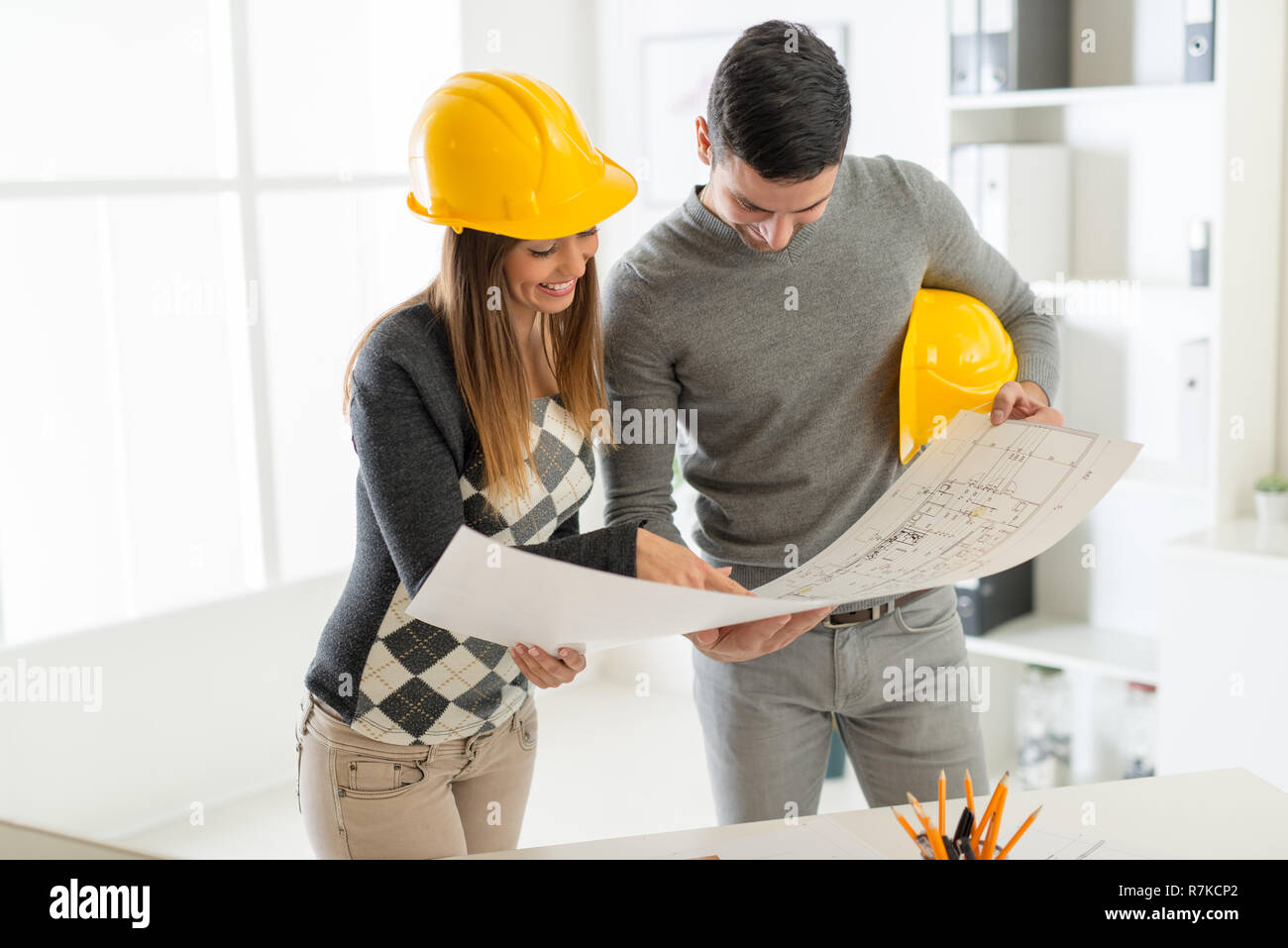 Smiling architect looking the architectural plans in office Stock Photo ...